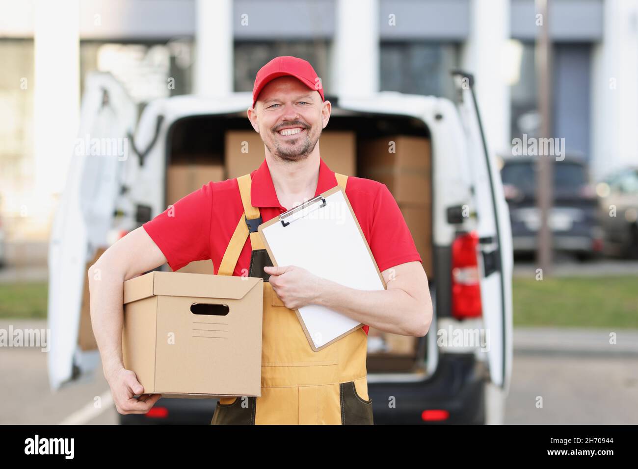 Happy postman with cardboard package and delivery receipt paper on ...