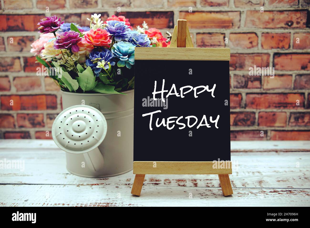 Happy Tuesday text on black wooden easel and vase with flowers bouquet ...