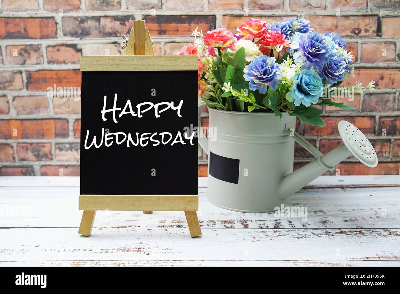 Happy Wednesday text on black wooden easel and vase with flowers ...