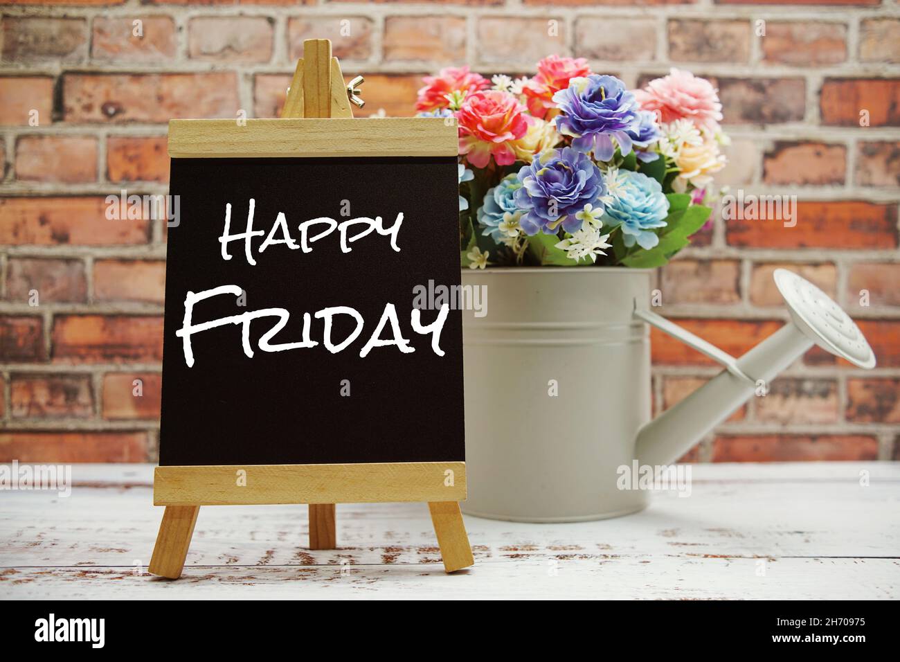 Happy Friday text on black wooden easel and vase with flowers bouquet ...