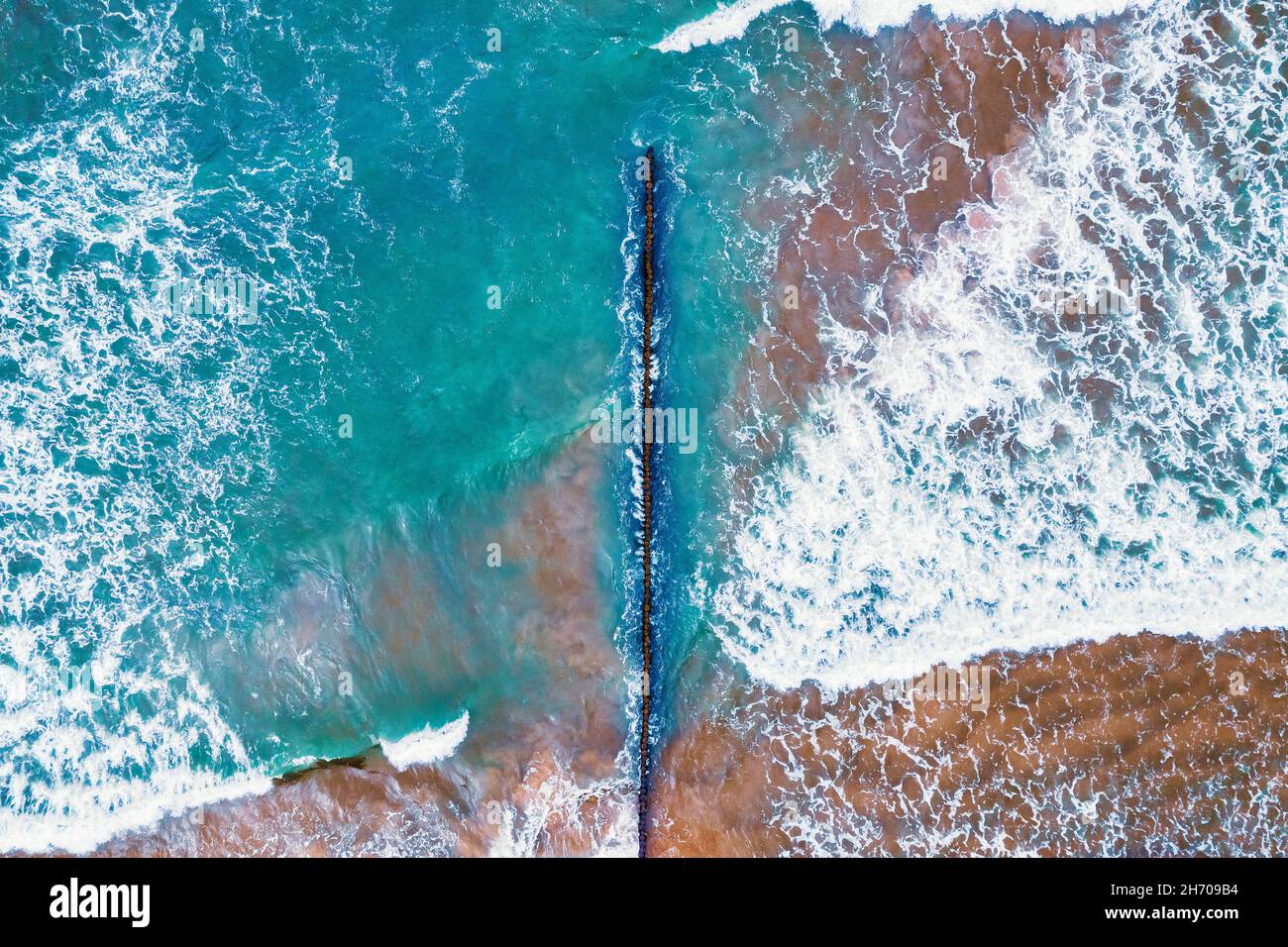 Aerial top view of breakwater with wave of sea, clean blue water around ...