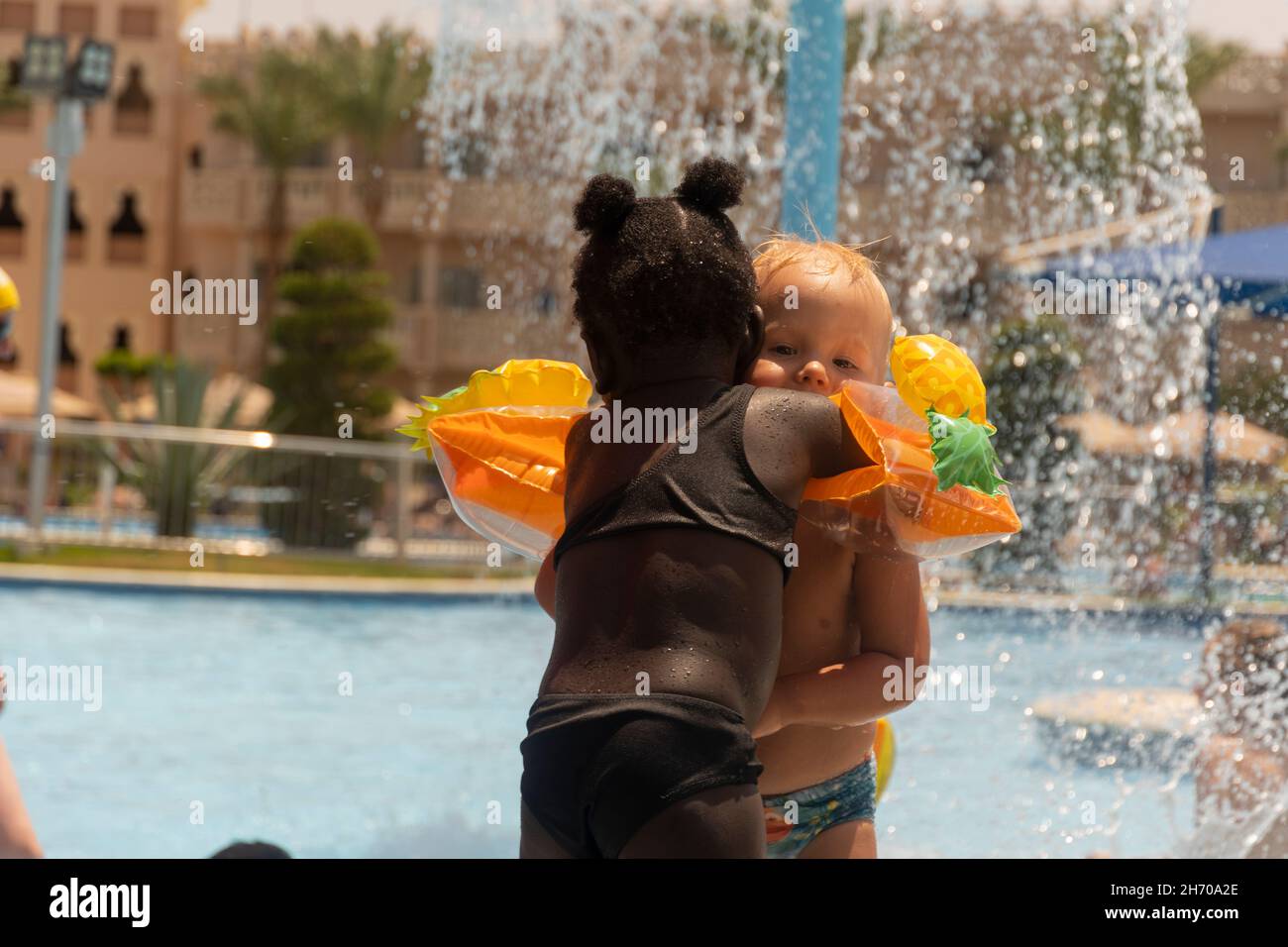 Children hug in the pool. Happy kids, friendship. different skin color ...