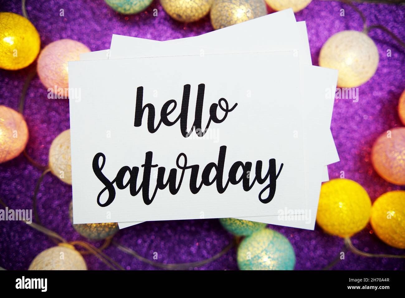 Hello Saturday text on paper card top view on purple bokeh background ...