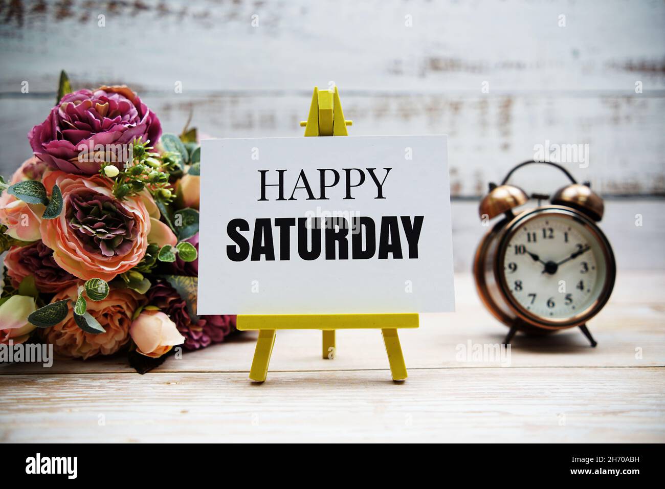 Happy Saturday text with flower bouquet and alarm clock on wooden ...