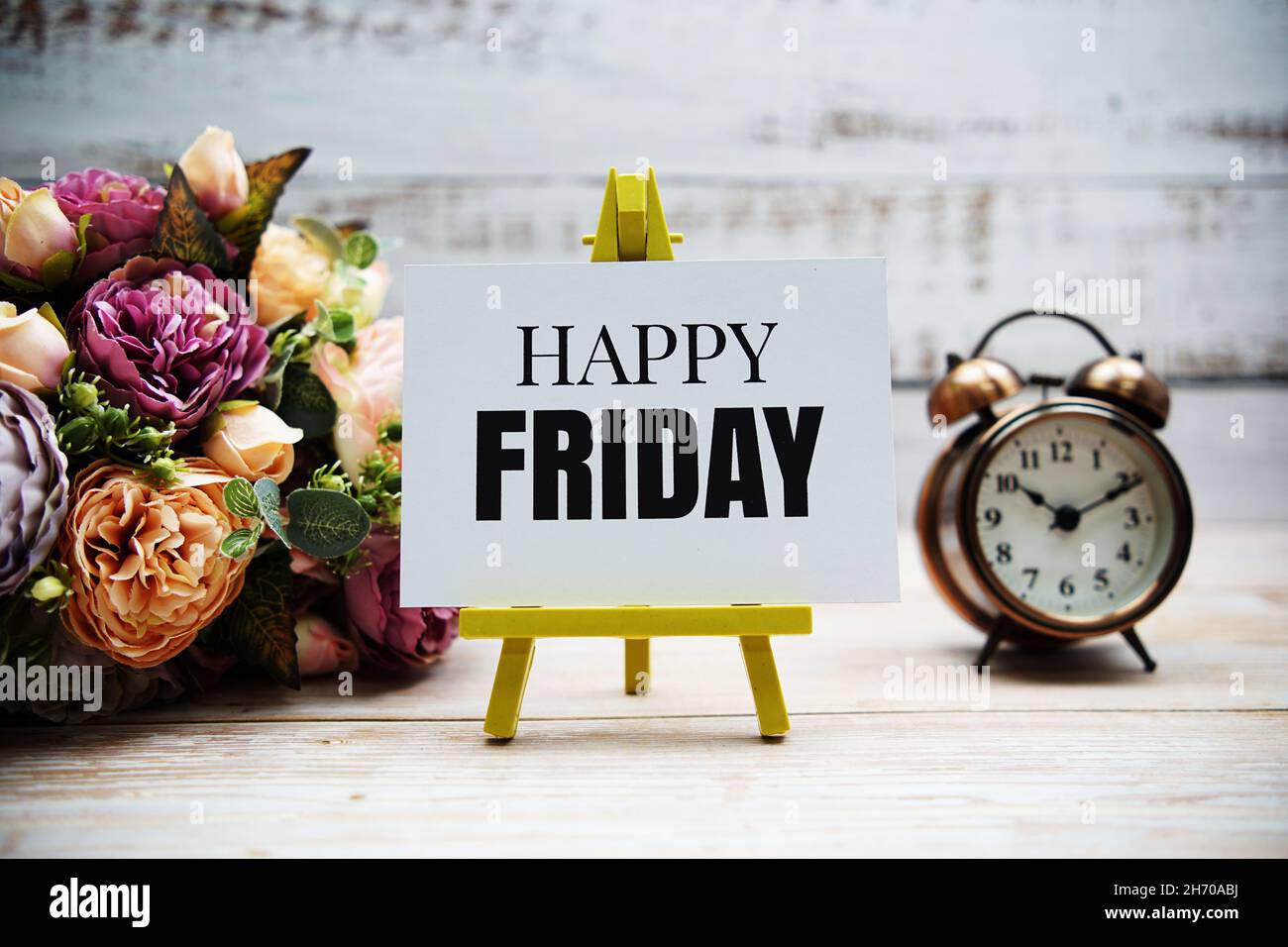 Happy Friday text with flower bouquet and alarm clock on wooden ...