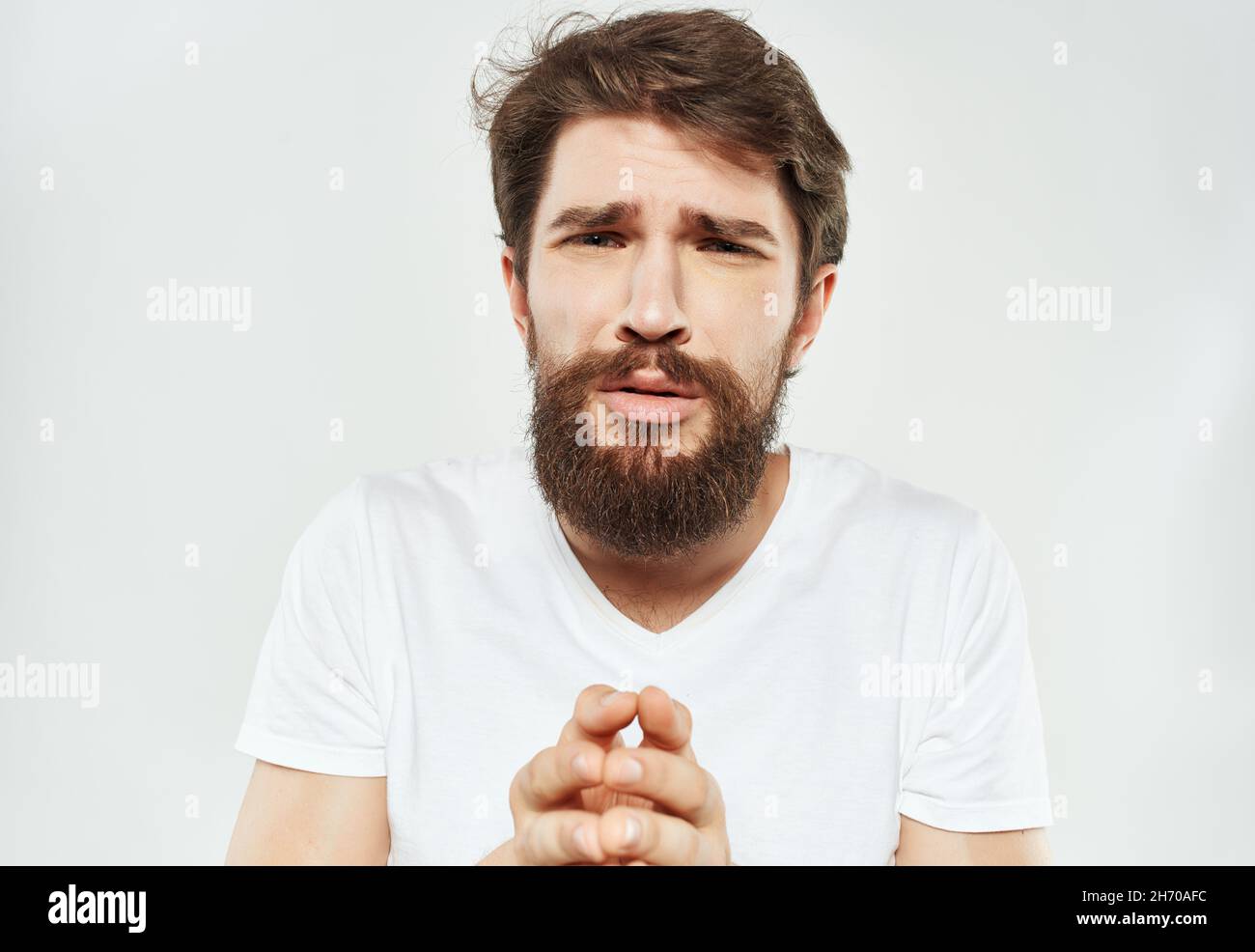 bearded man in a white t-shirt hand gestures anger light background ...