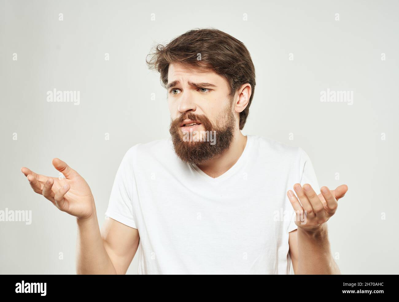 Man in a white t-shirt hand gestures anger light background Stock Photo ...