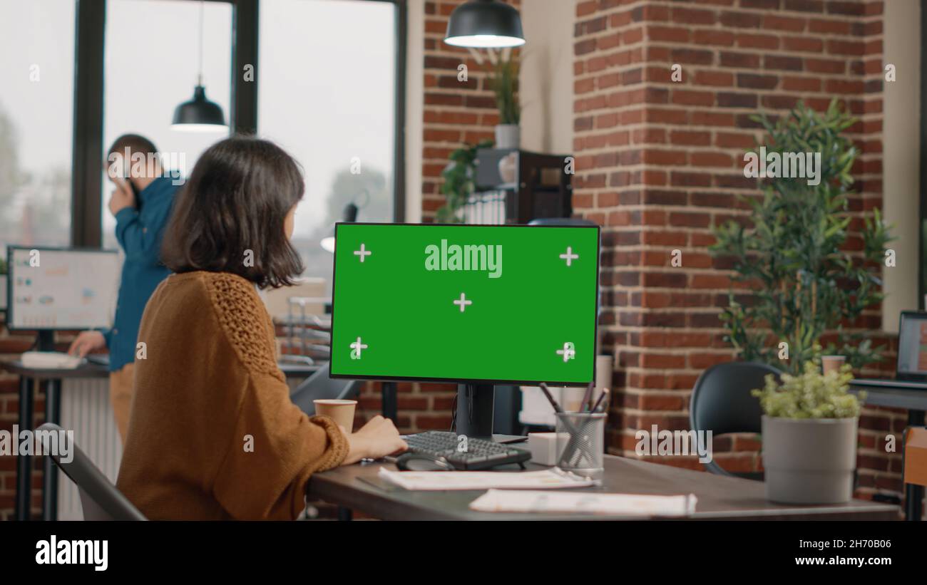 Employee looking at horizontal green screen on computer display at desk ...