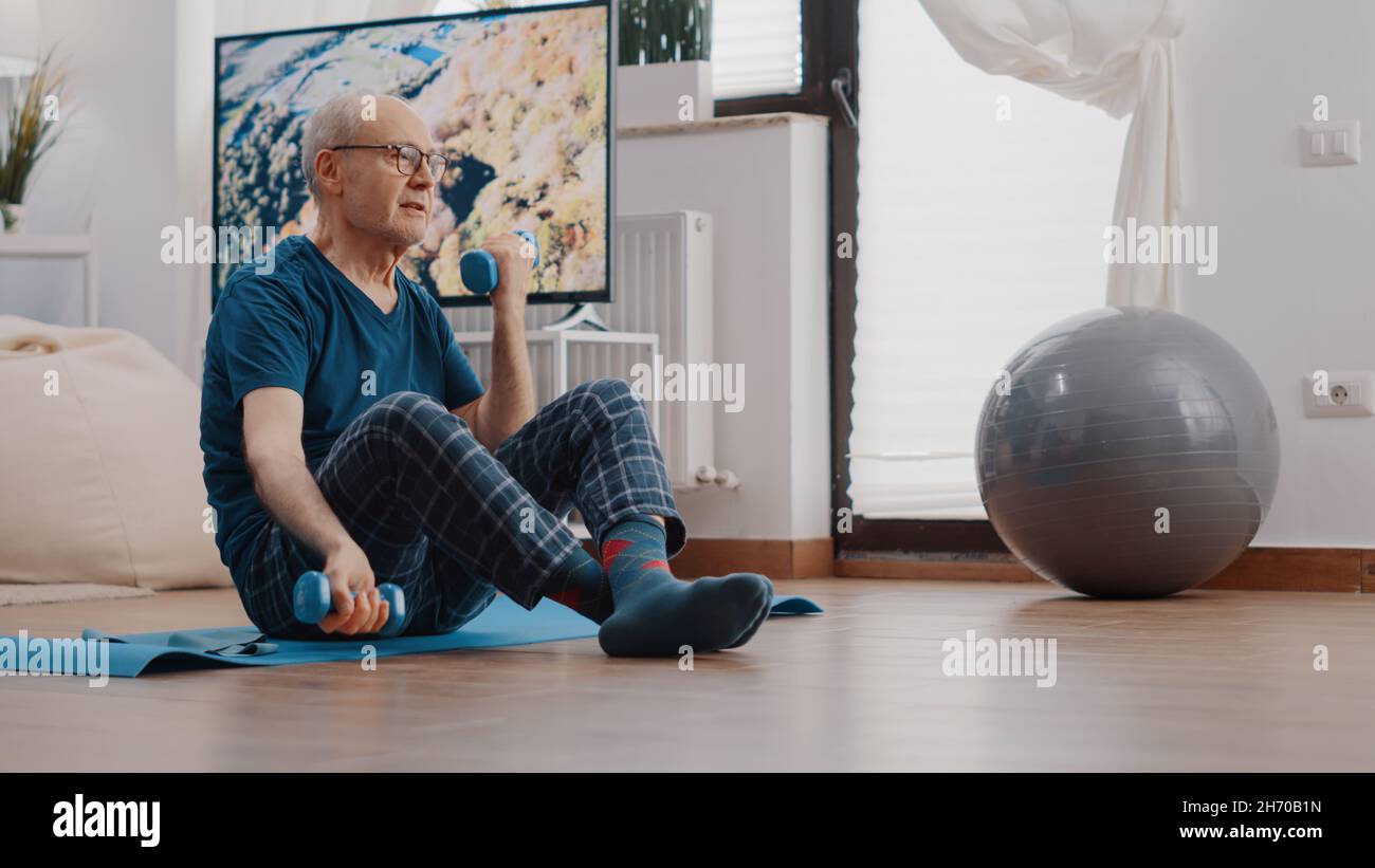 Senior person using dumbbells to exercise and train arms muscles ...