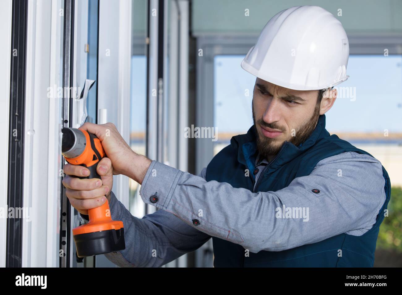 concentrated man with screwdriver tightens window Stock Photo - Alamy