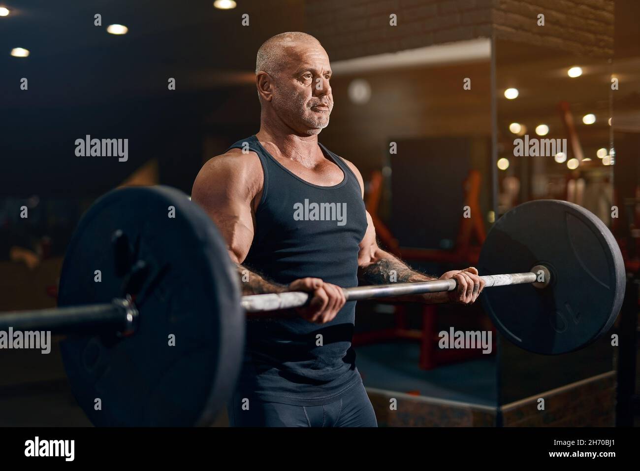 adult sportsman pumping up biceps muscles while workout in gym with ...