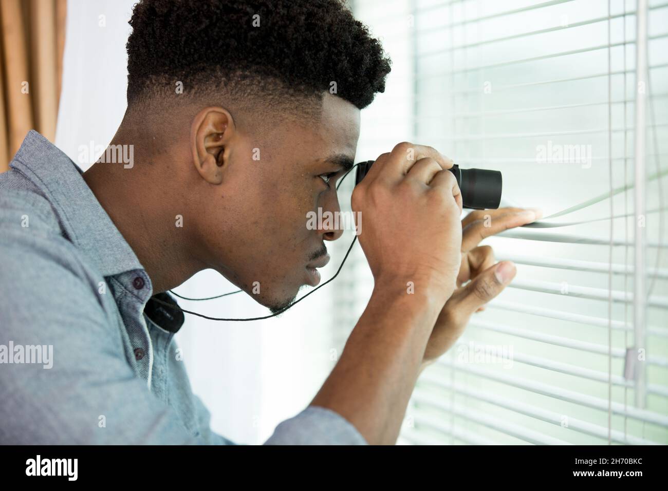 suspicious man looking through window blinds with binoculars Stock ...