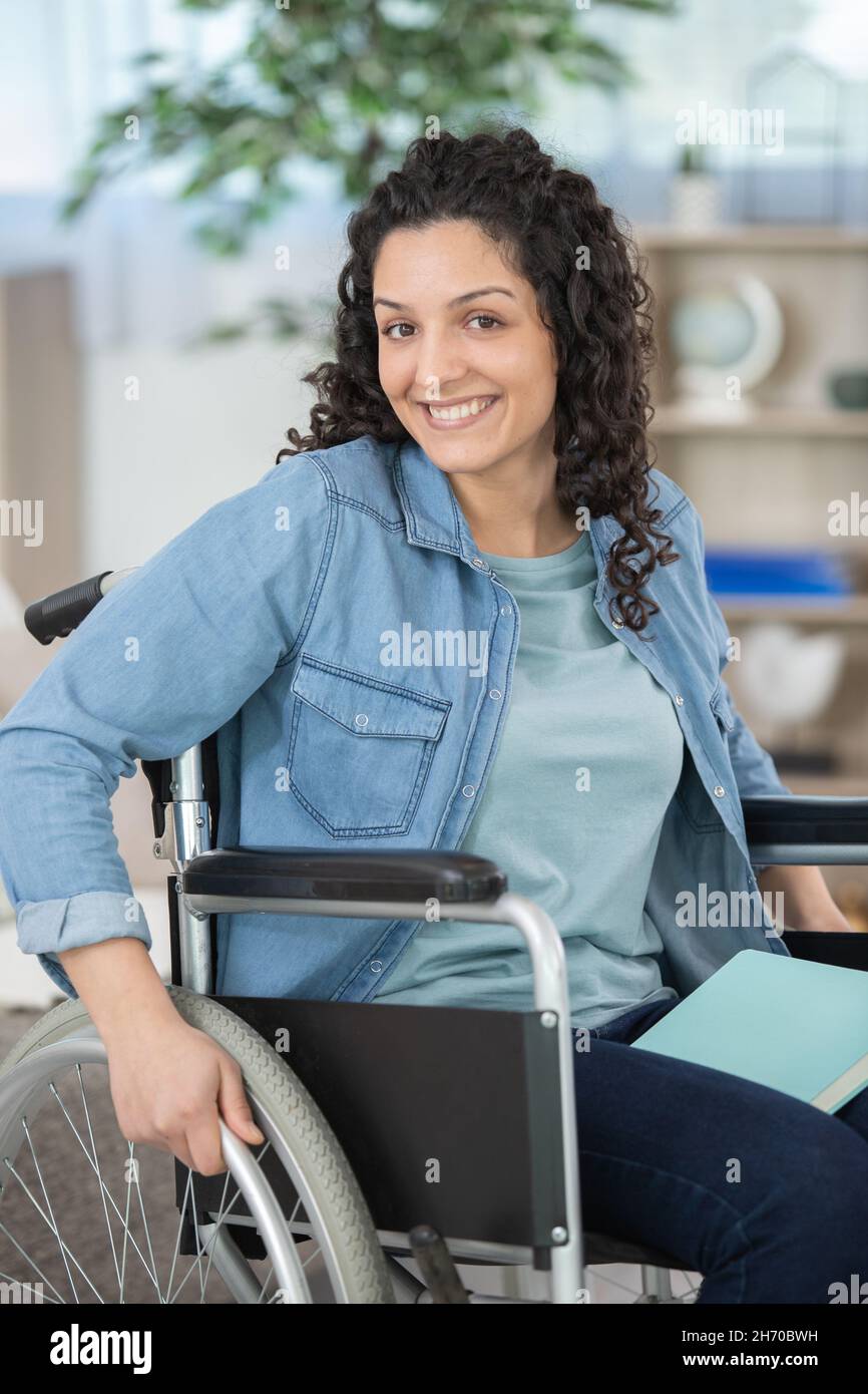 happy young disabled woman in wheelchair with book Stock Photo - Alamy