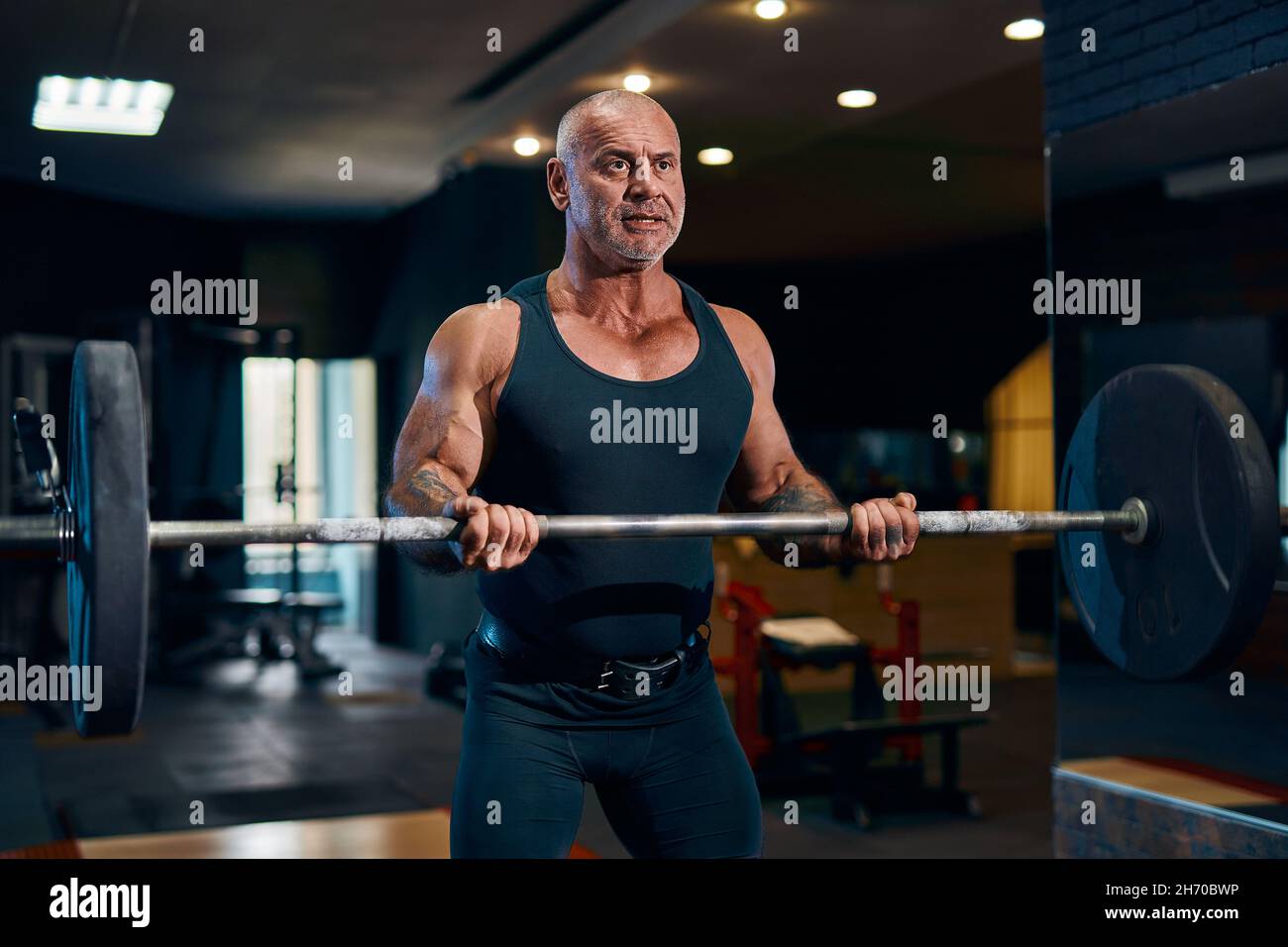 adult bodybuilder pumping up biceps muscles while workout in gym with ...