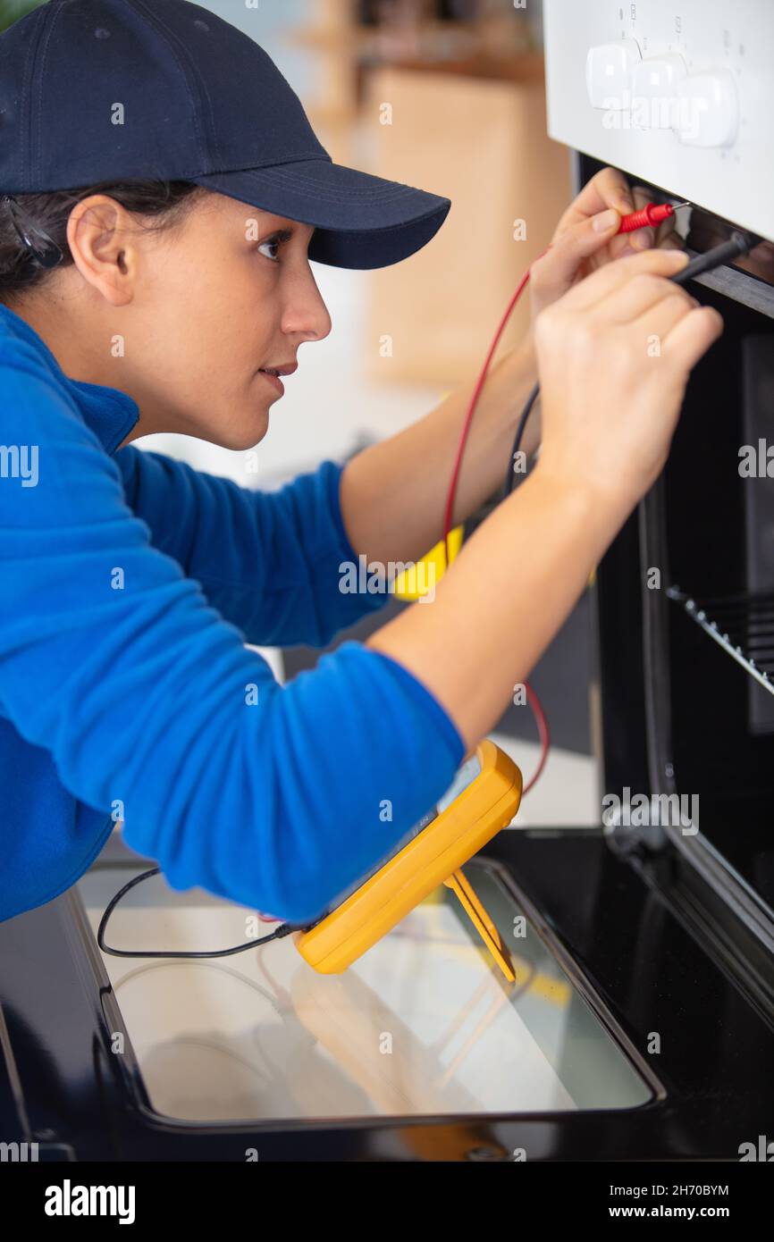 young woman checks oven malfunction with multimeter Stock Photo - Alamy