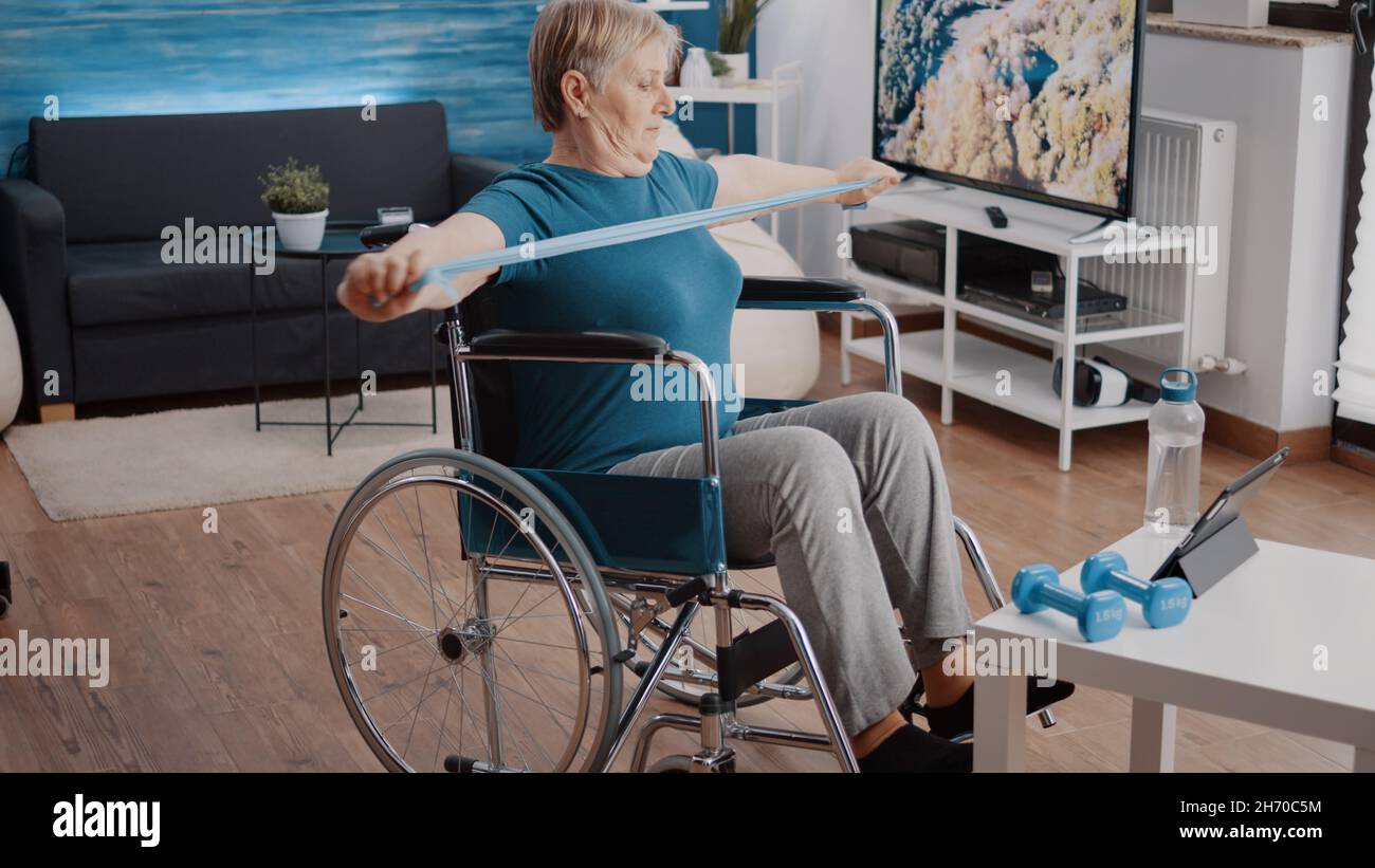 Person sitting in wheelchair and pulling resistance band to stretch ...