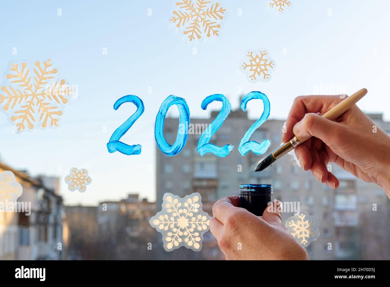 A woman's hand holding a brush with blue paint and writing the numbers ...