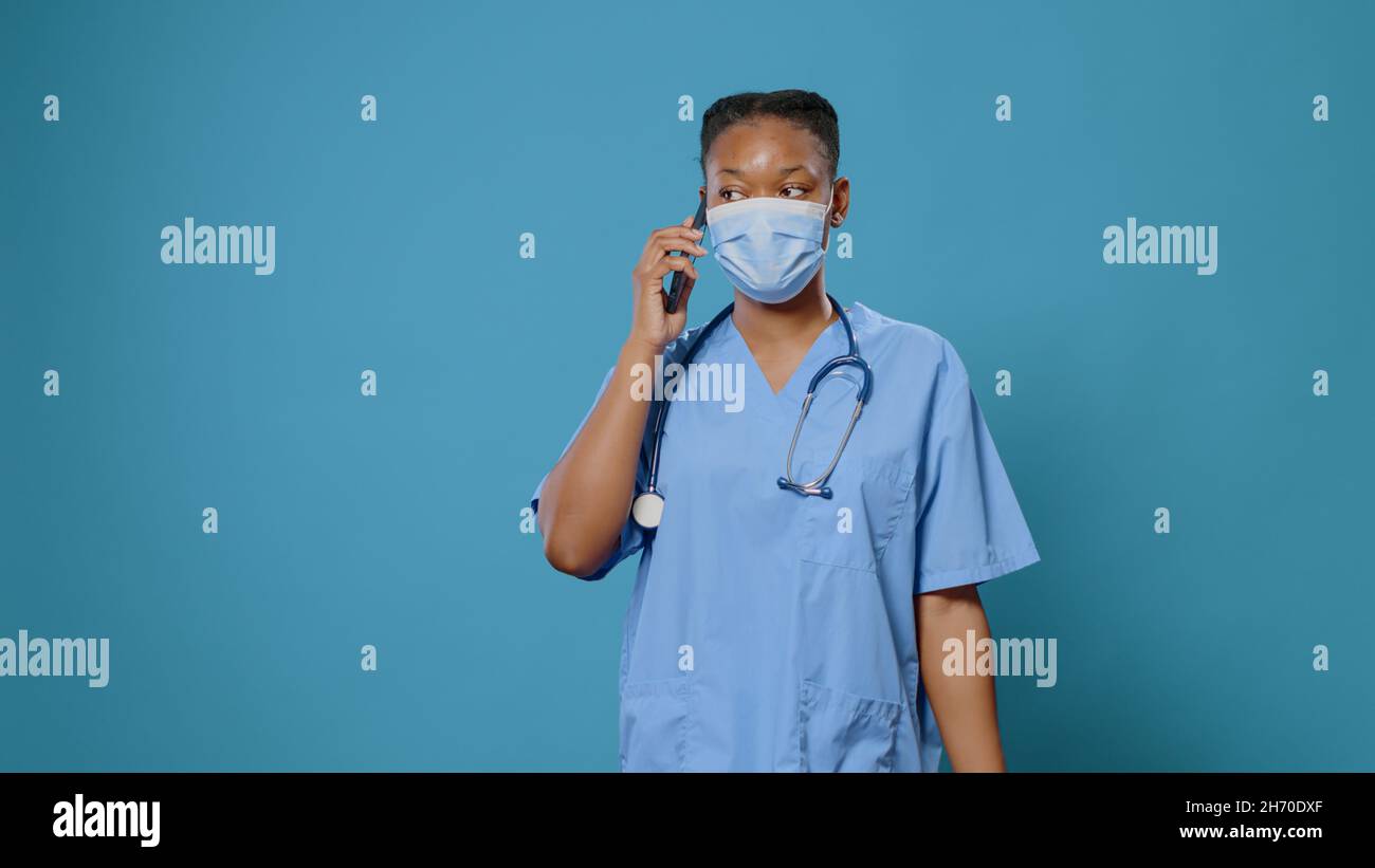 African american assistant with face mask talking on phone call while ...