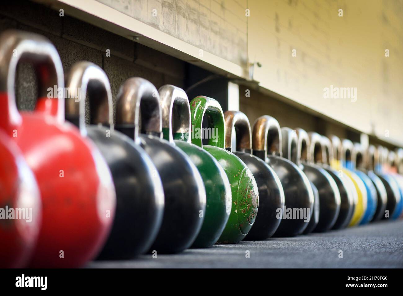 Long row of colorful heavy kettlebells in gym with diminishing ...