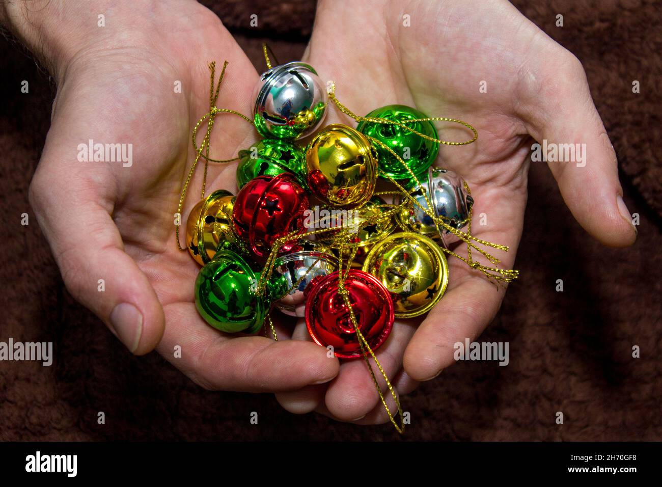 Multi-colored jingle bells in men's hands. Selective focus. Dark ...
