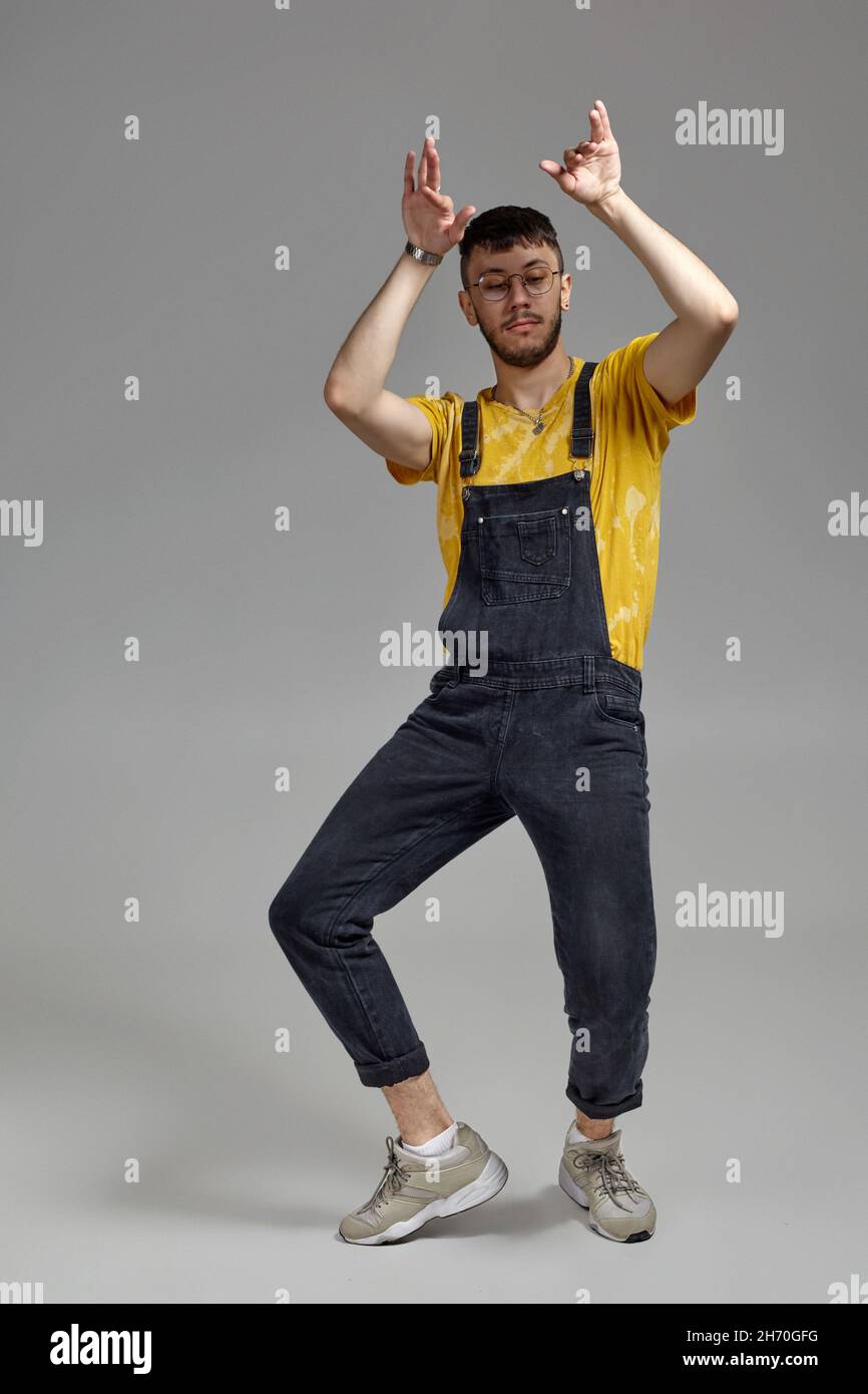 Full-length portrait of a funny guy dancing in studio on a gray ...