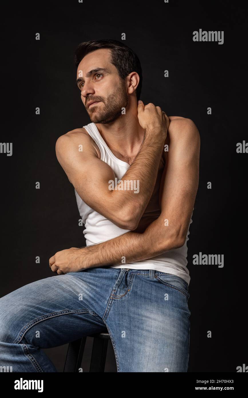 Classic portrait of young handsome bearded sad man in white undershirt ...
