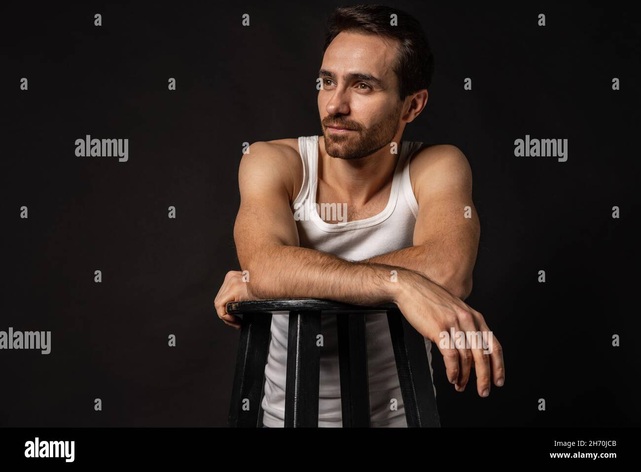 Classic portrait of young handsome bearded sad man in white undershirt ...