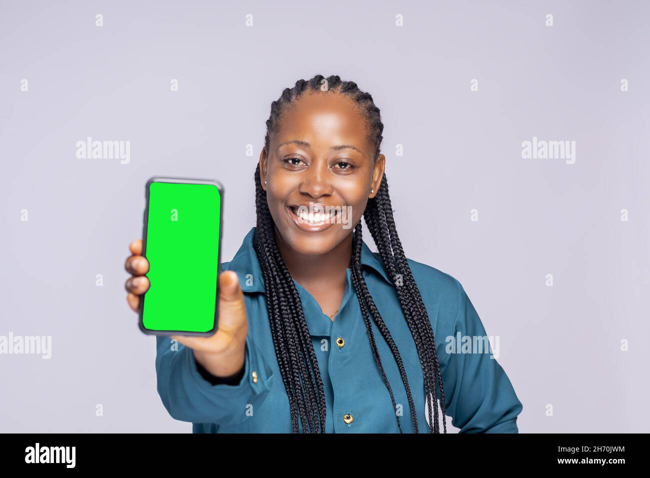 Young African woman shows the smartphone screen with a smile on her ...