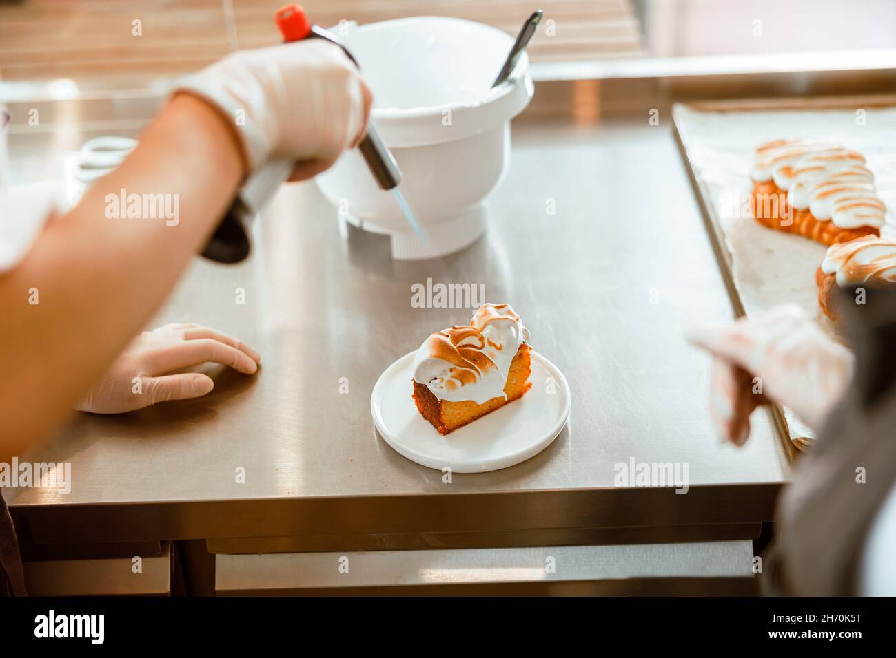 Professional confectioner makes pattern on cake with cream using gas ...