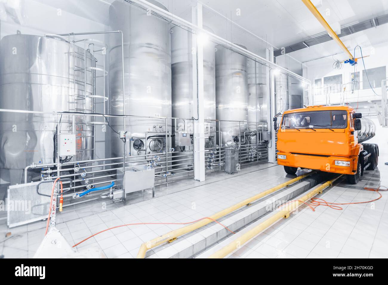 Milk tanker truck pumps products into steel storage tanks, dairy ...