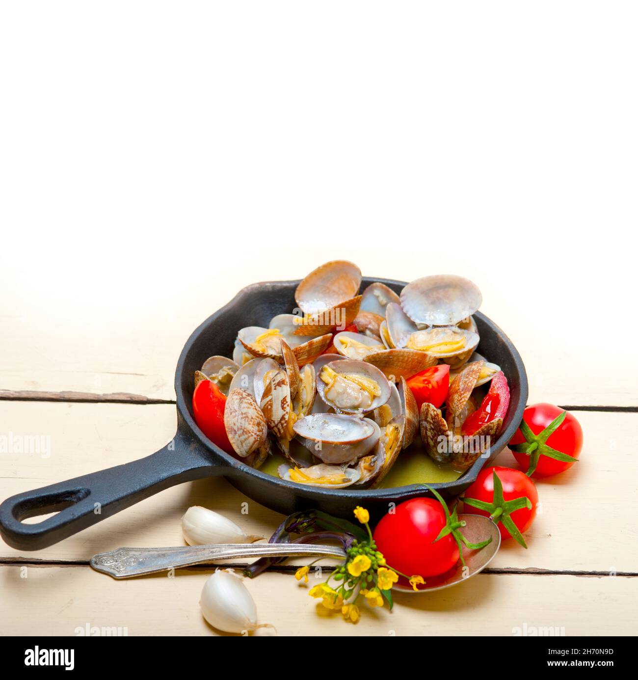 fresh clams stewed on an iron skillet over wite rustic wood table Stock ...