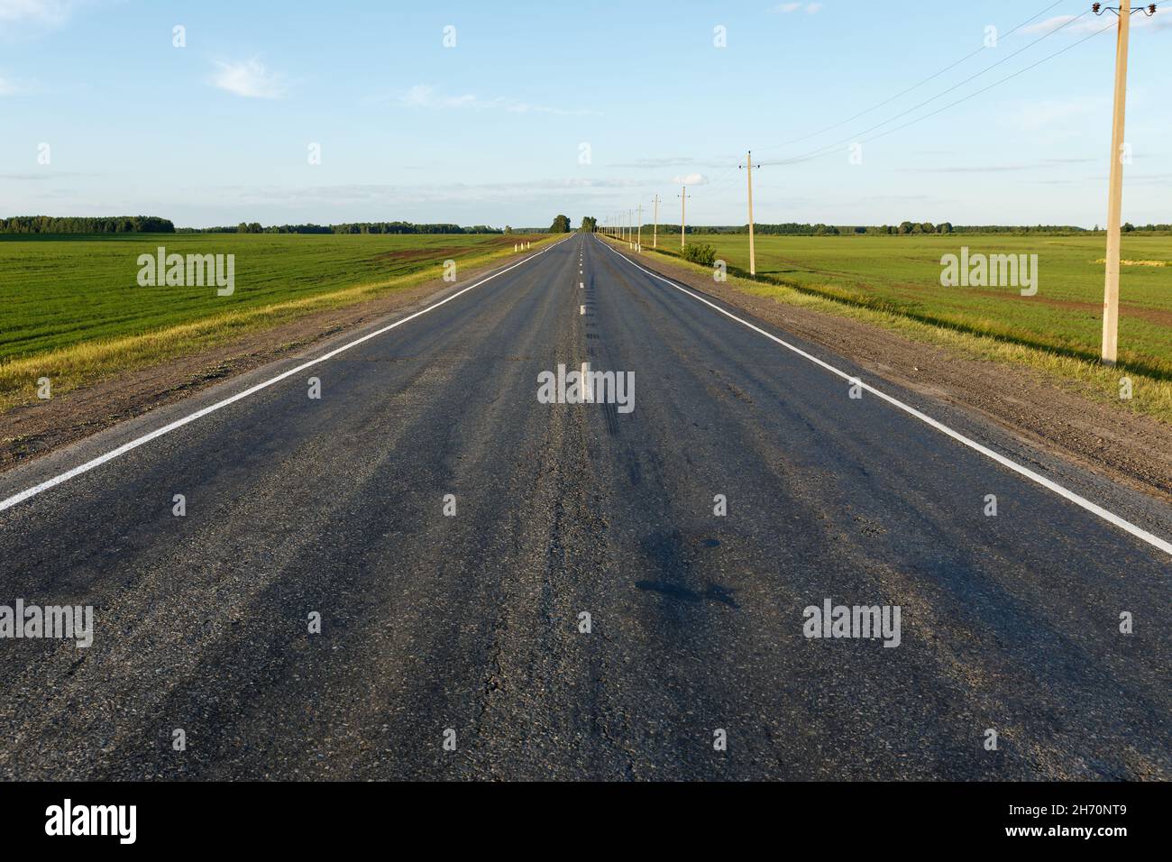 Countryside asphalt road with marking. Electricity pylon along the road ...