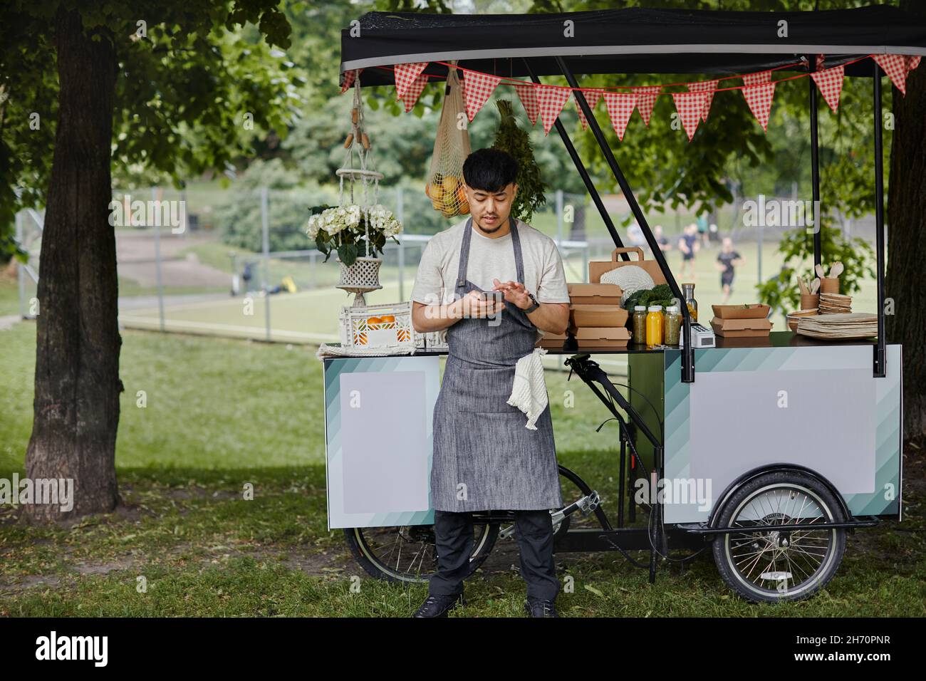 Man standing in front of food stall Stock Photo - Alamy