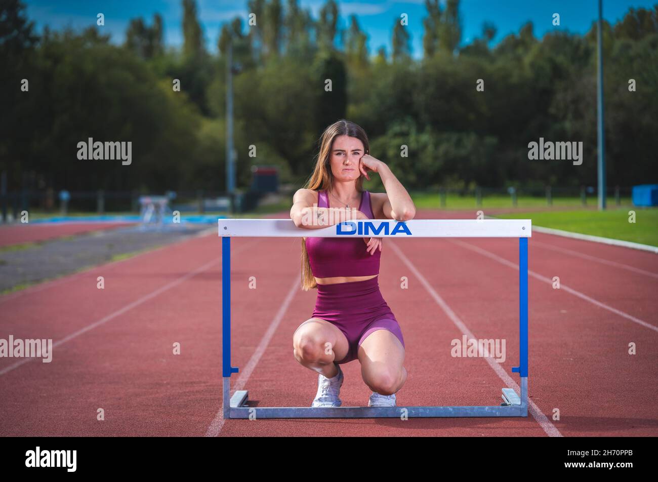 Athlete model girl posing with hurdles on the running track Stock Photo ...