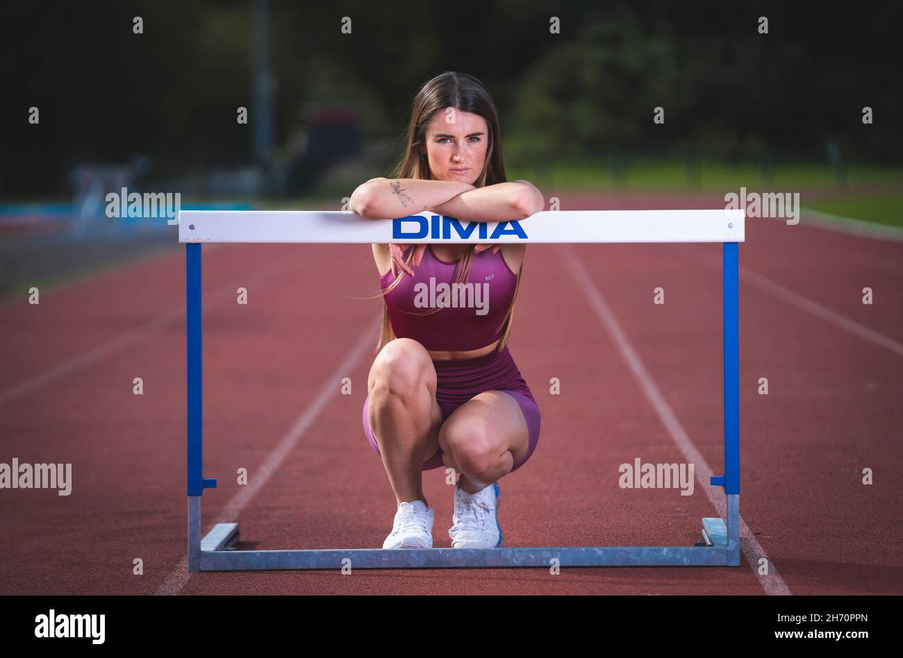 Athlete model girl posing with hurdles on the running track Stock Photo ...