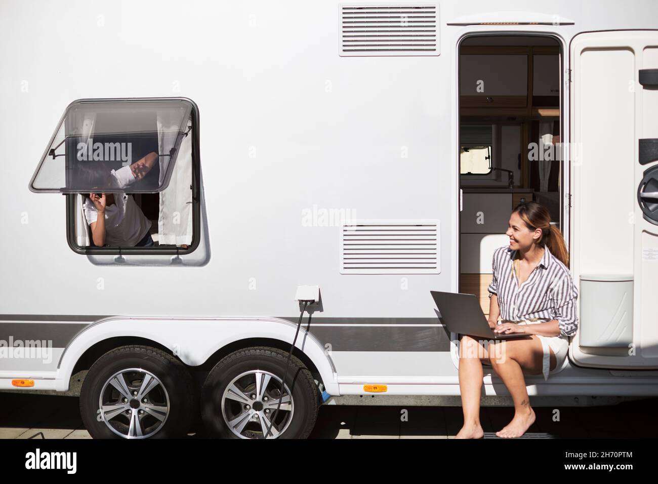 Woman sitting at caravan door Stock Photo - Alamy