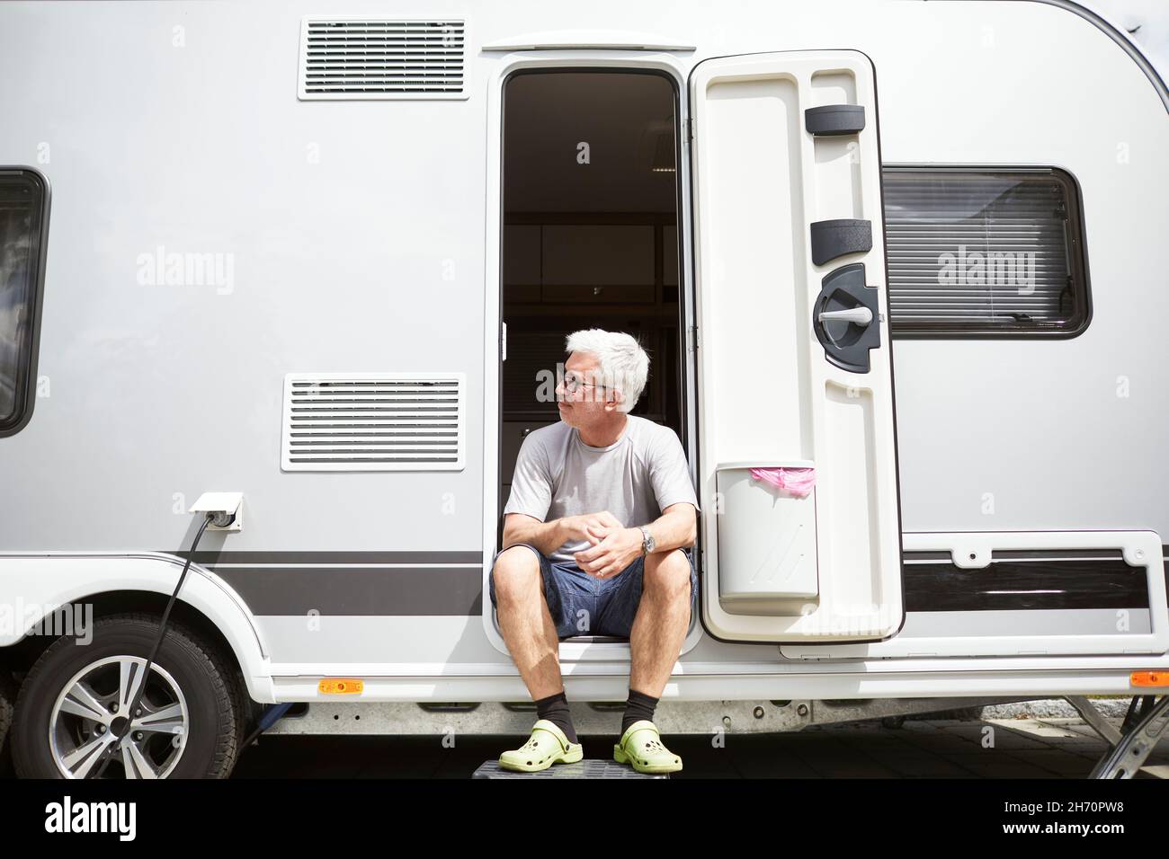 Man sitting at caravan door Stock Photo - Alamy