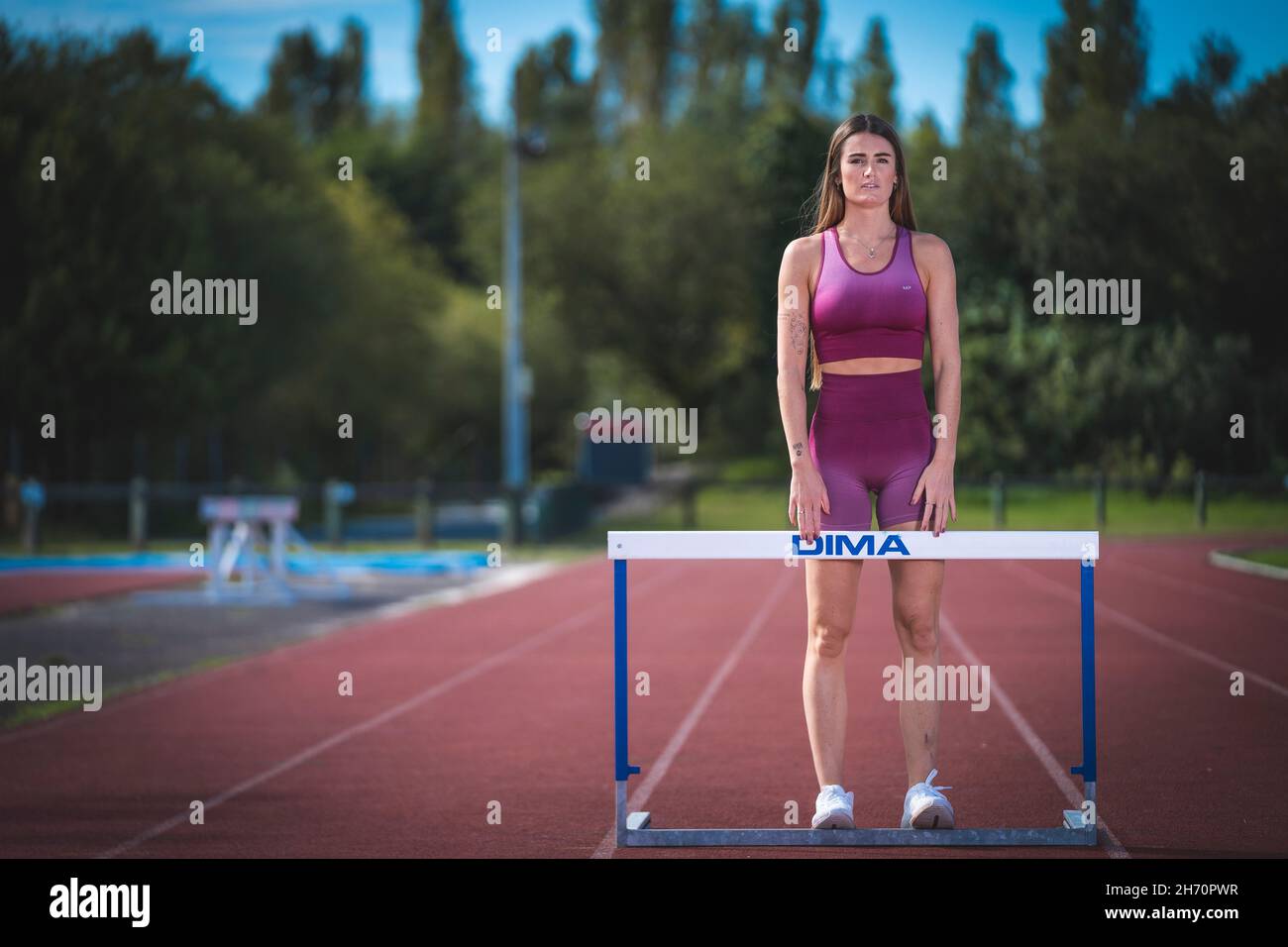 Athlete model girl posing with hurdles on the running track Stock Photo ...