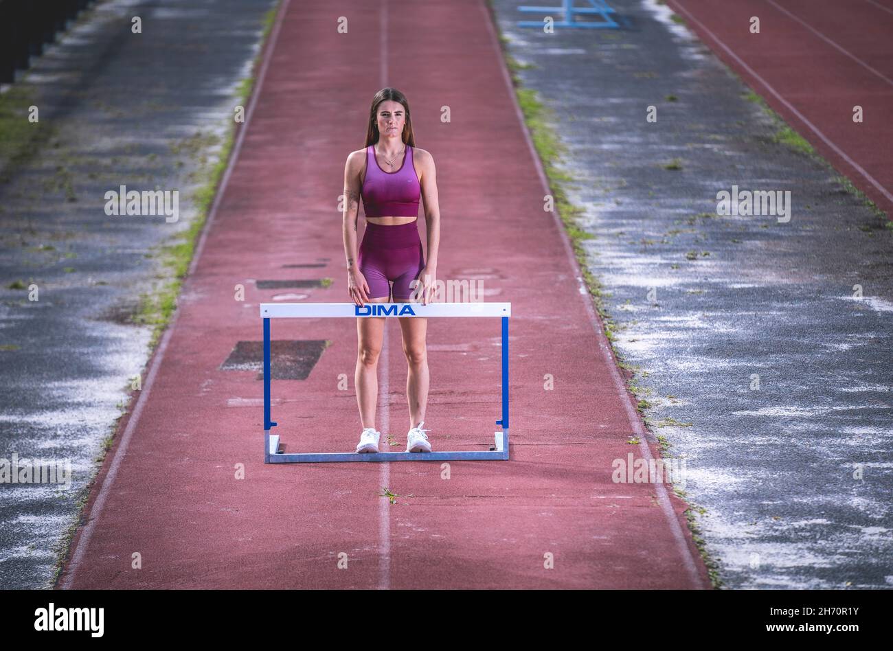 Athlete model girl posing with hurdles on the running track Stock Photo ...