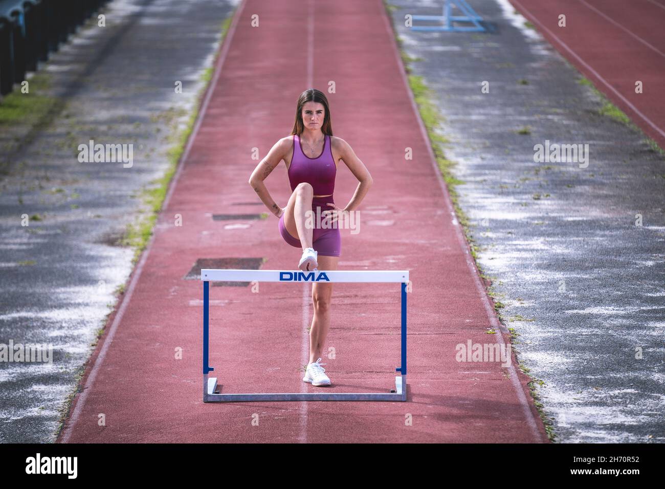 Athlete model girl posing with hurdles on the running track Stock Photo ...