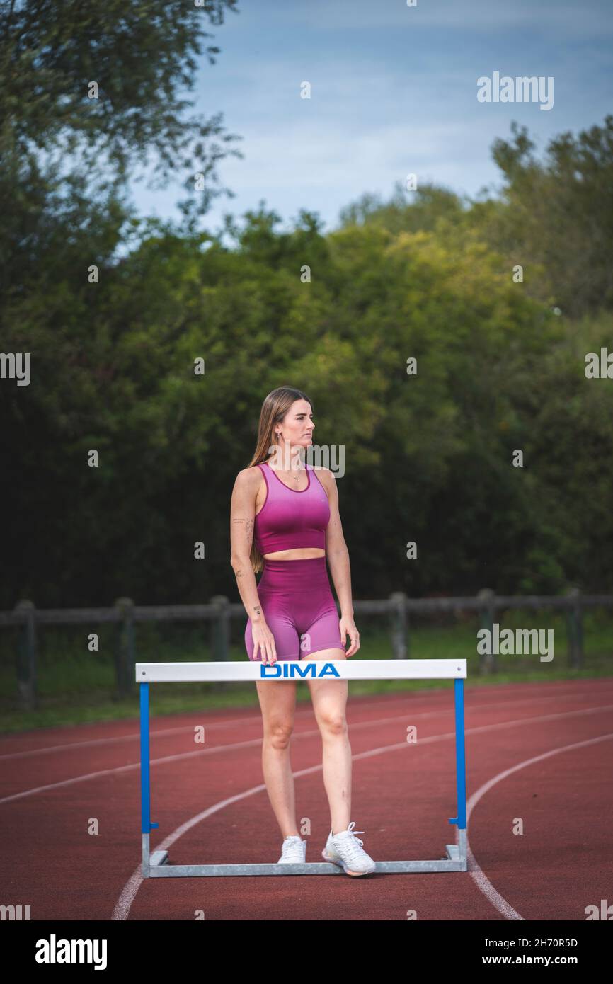 Athlete model girl posing with hurdles on the running track Stock Photo ...