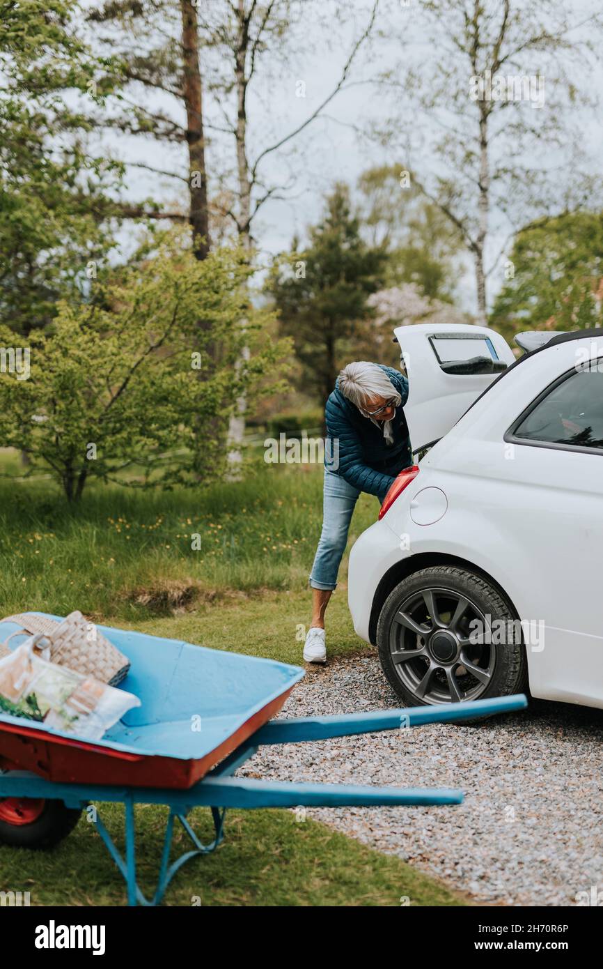 Woman standing in front of open car boot Stock Photo - Alamy