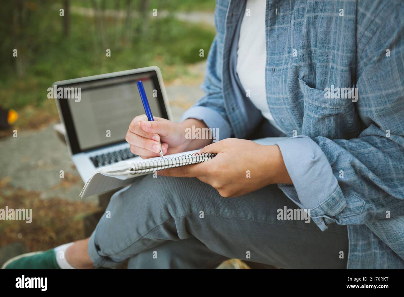Young woman with notepad and laptop sitting on bench Stock Photo - Alamy