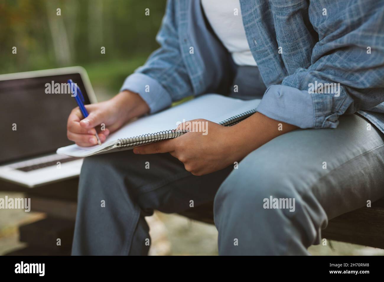 Young woman with notepad and laptop sitting on bench Stock Photo - Alamy