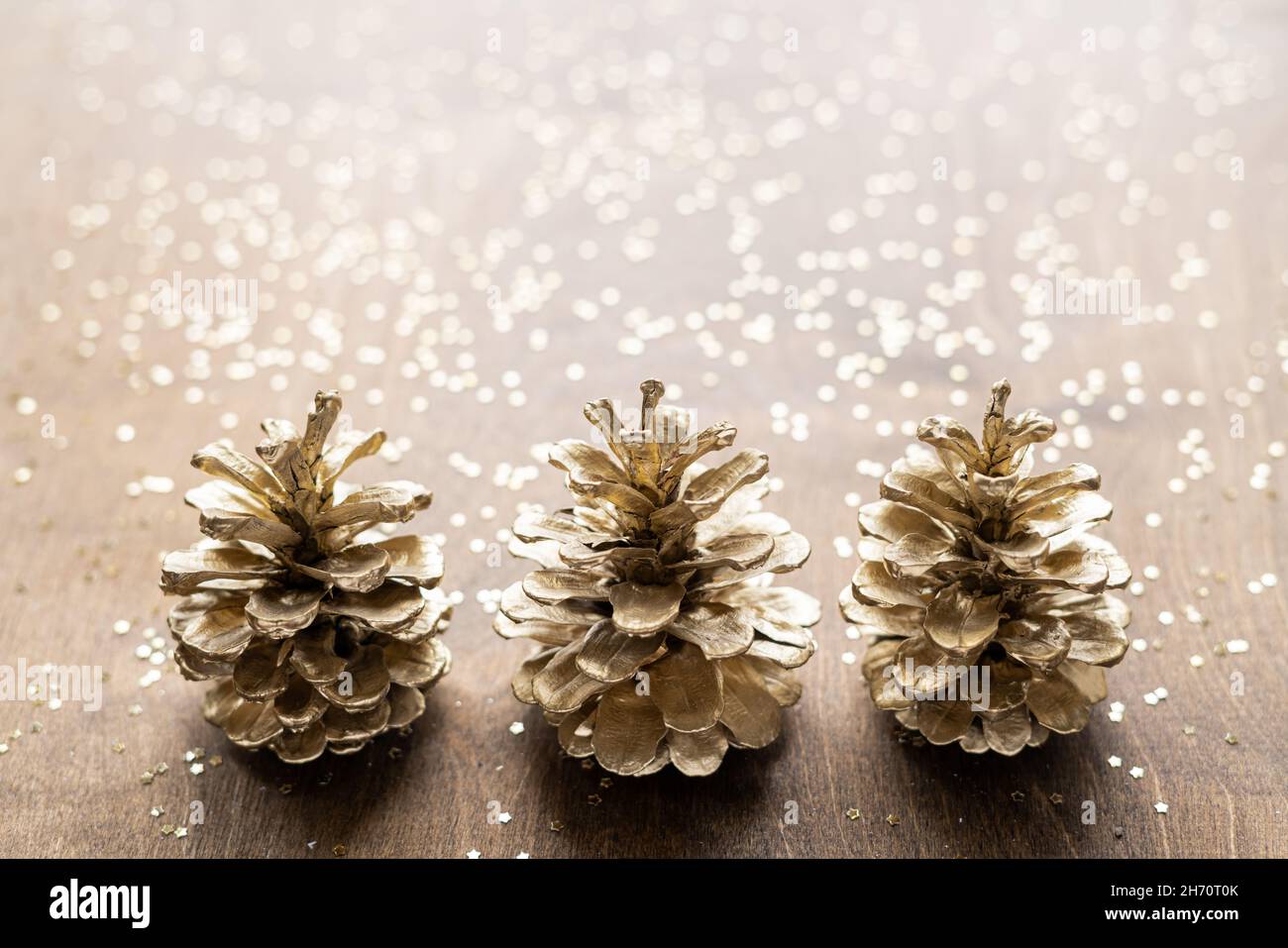 natural golden cones on a wooden table with gold spangles in the shape ...