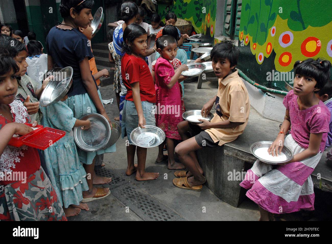 Kids waiting in a queue for their turn to receive food while other ...