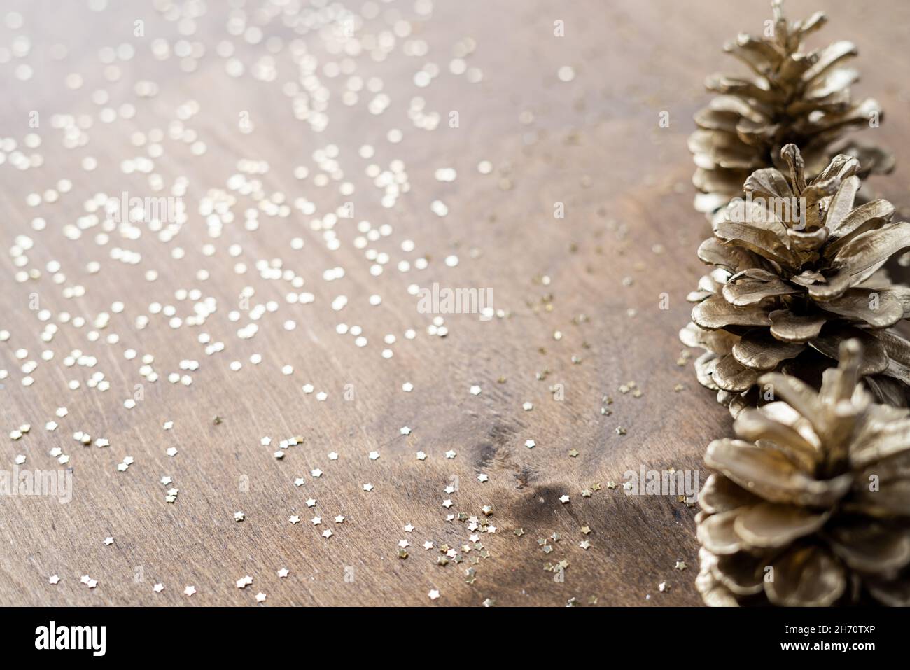 natural golden cones on a wooden table with gold spangles in the shape ...