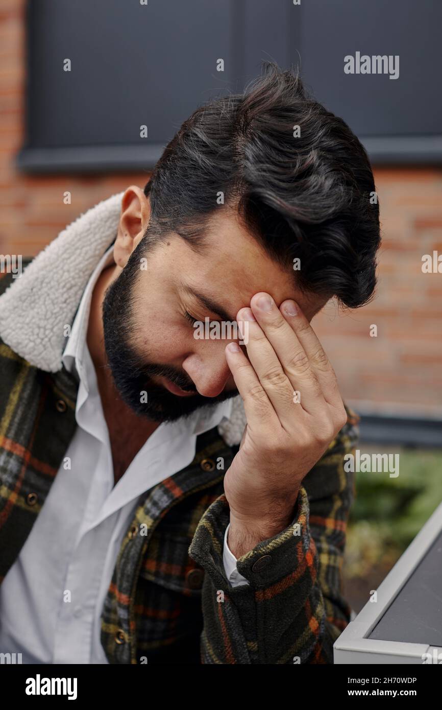 Young man touching forehead Stock Photo - Alamy