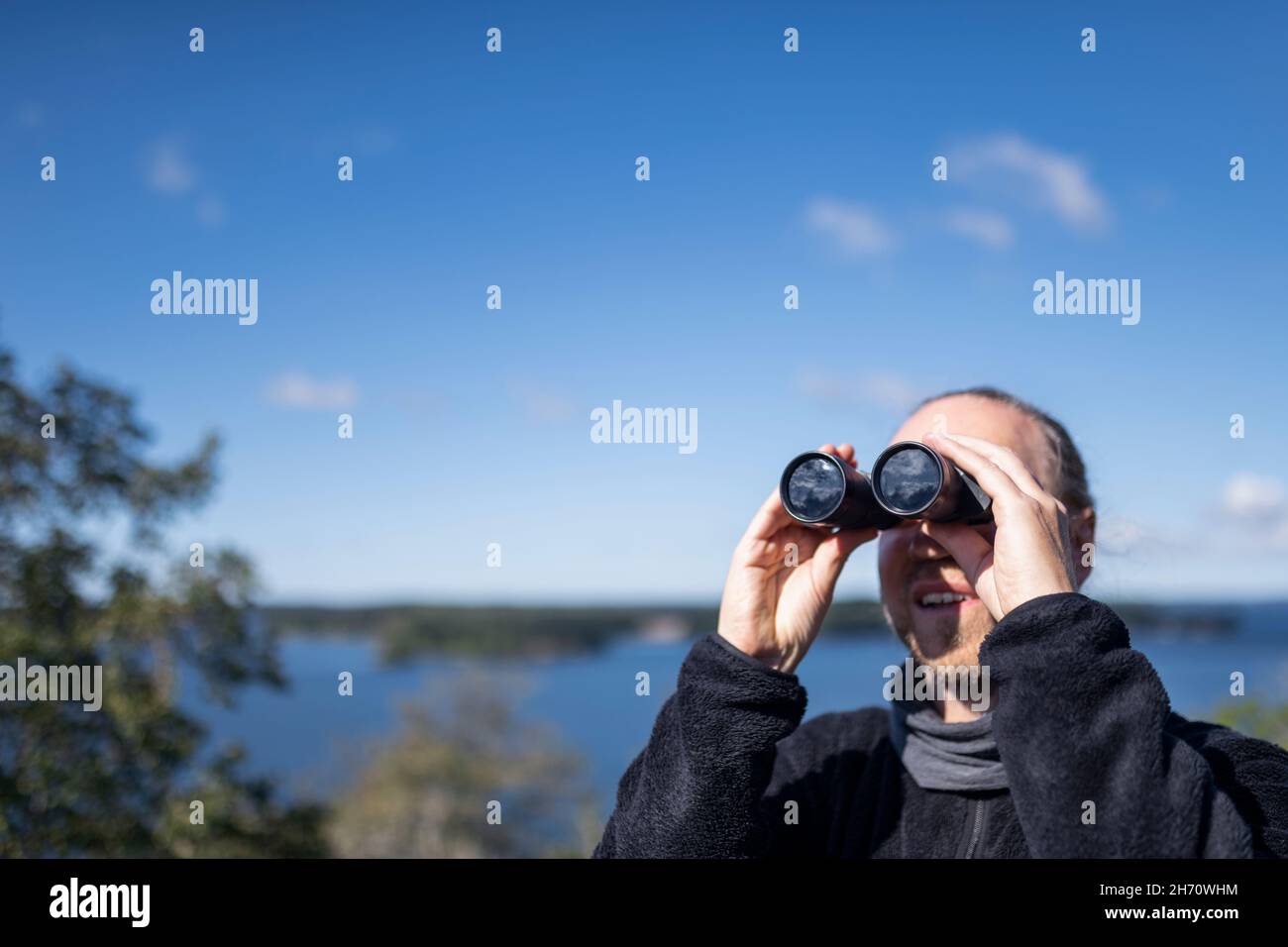 Man looking through binoculars Stock Photo - Alamy