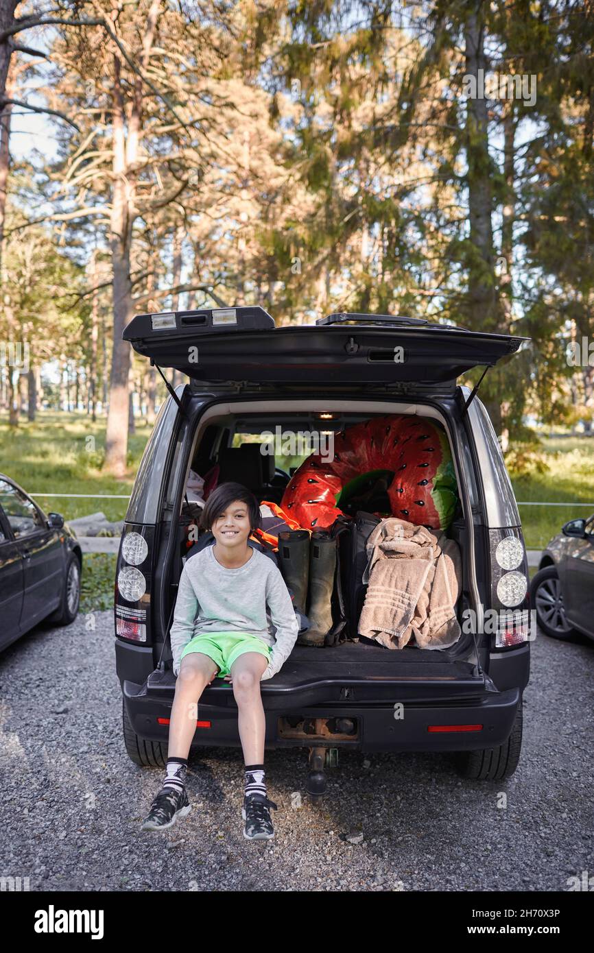 Smiling boy sitting in open boot Stock Photo - Alamy